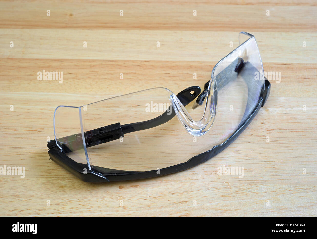 A pair of plastic safety glasses atop a wood table top Stock Photo - Alamy