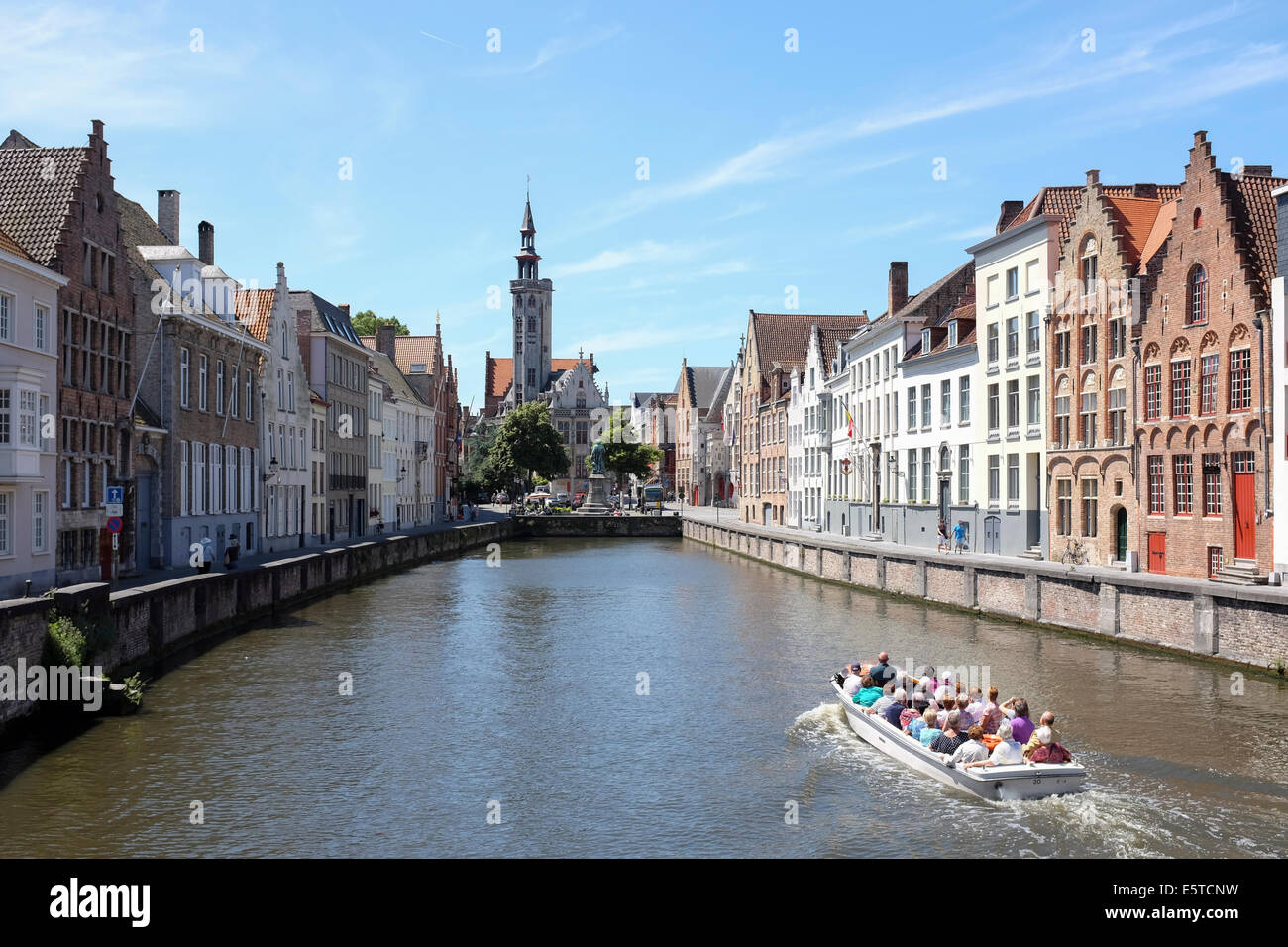 Tourists on a boat ride in canals of Bruges, Belgium. The Toll House in ...