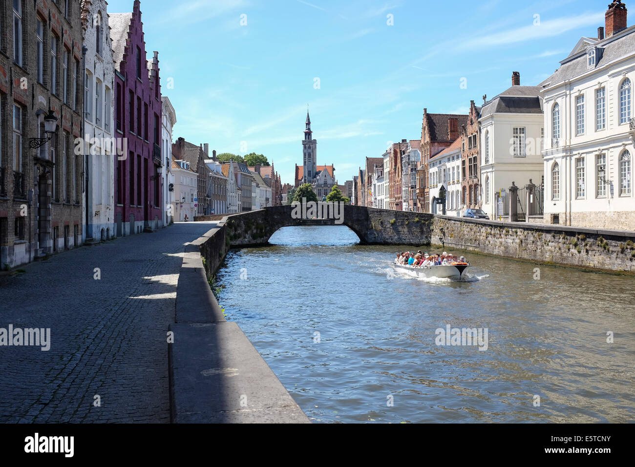 Tourists on a boat ride in canals of Bruges, Belgium. The Toll House in ...