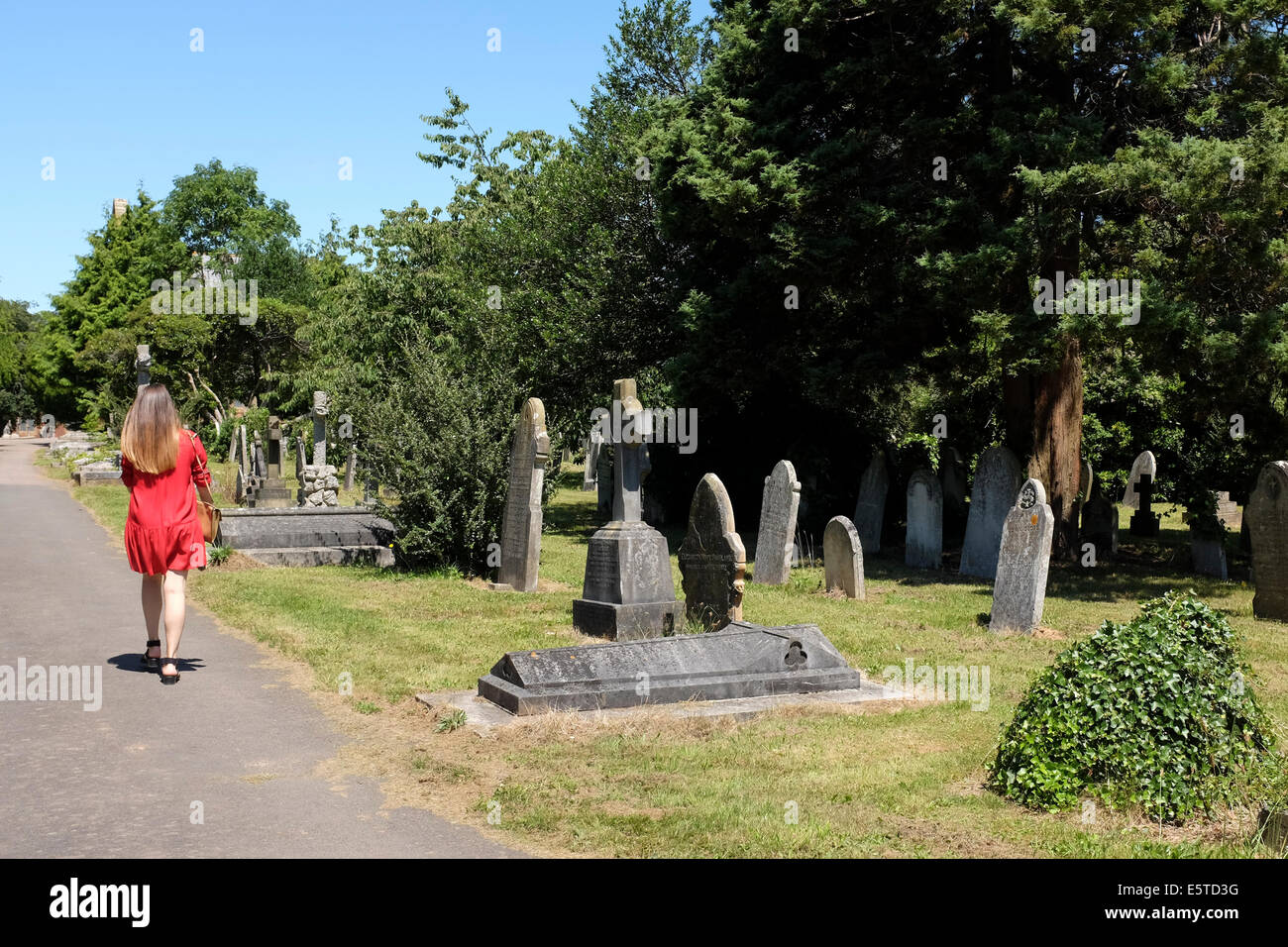 Woman dressed in red walking through the Higher Cemetery of Exeter ...