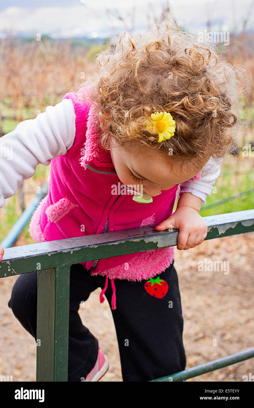 Curly haired girl climbing a railing Stock Photo - Alamy