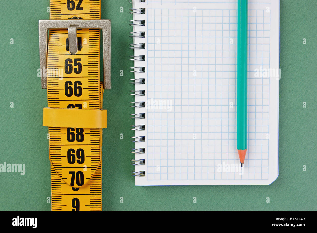 meter belt slimming and notepad with a pencil on the green background ...