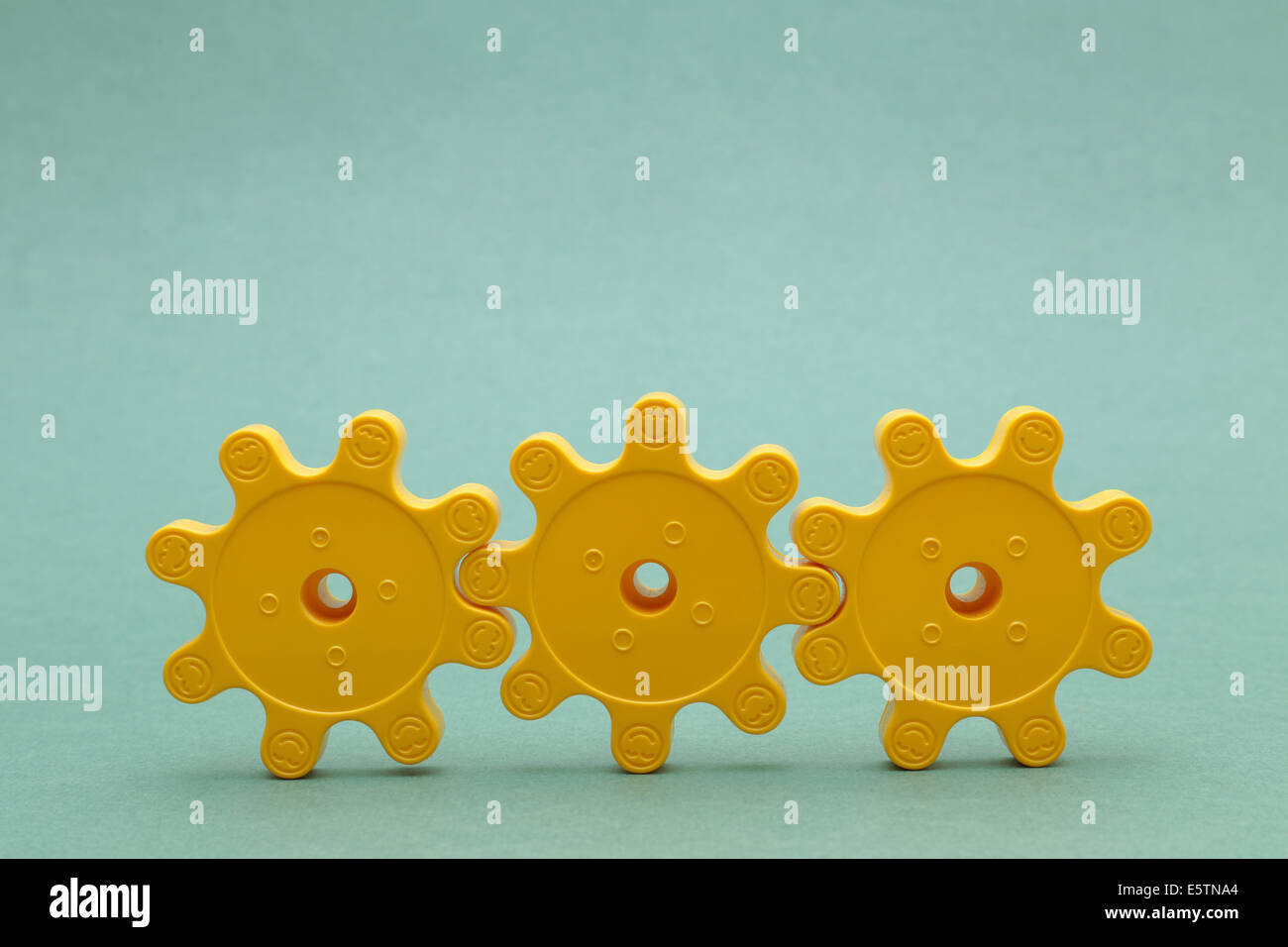 Three yellow plastic gears Stock Photo - Alamy
