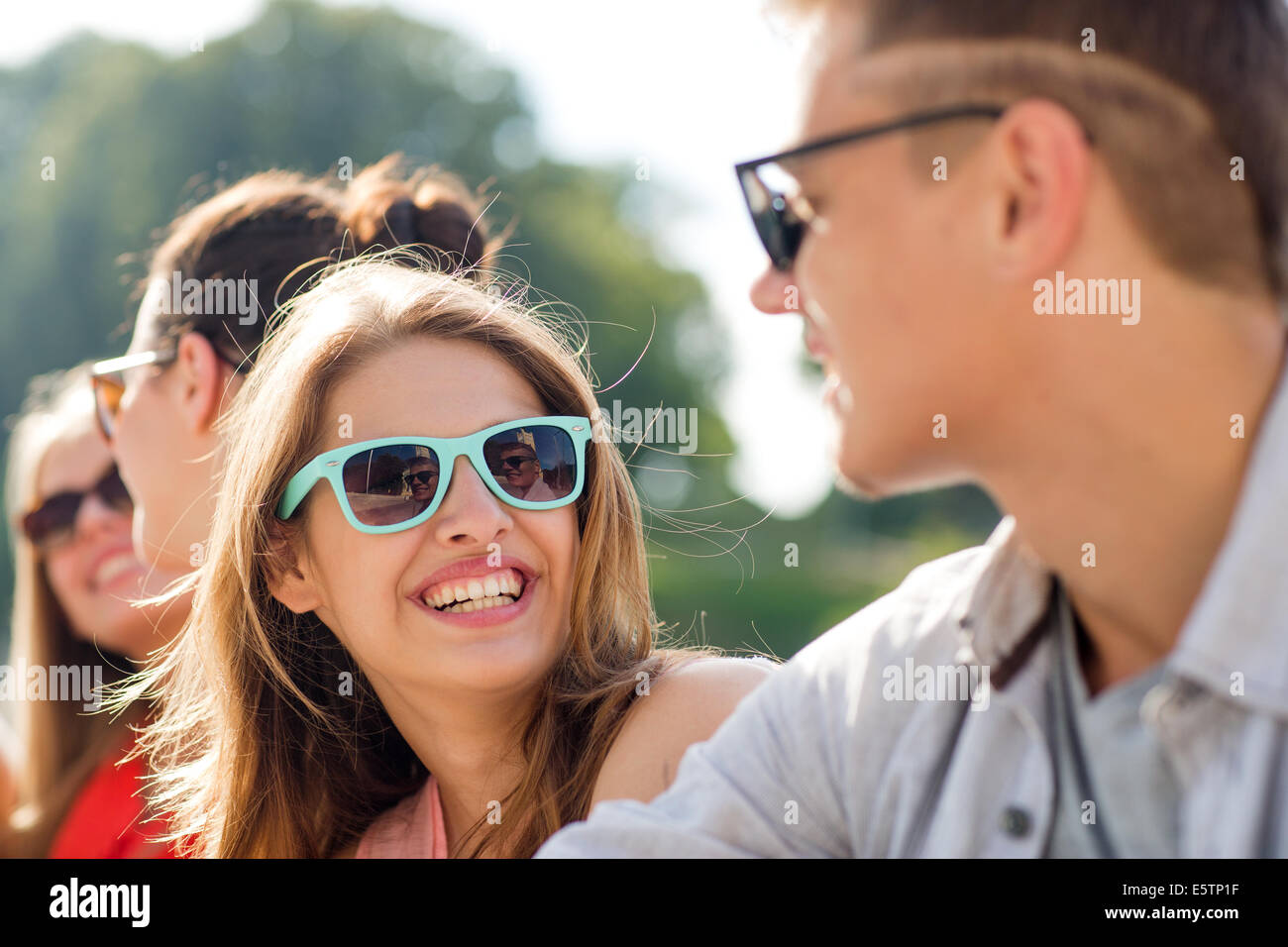 group of smiling friends sitting on city street Stock Photo - Alamy
