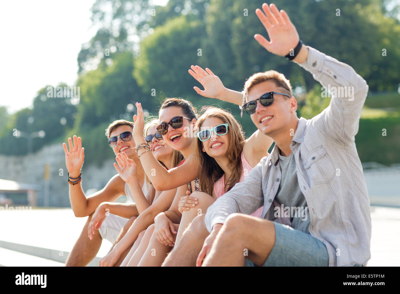 group of smiling friends sitting on city street Stock Photo - Alamy