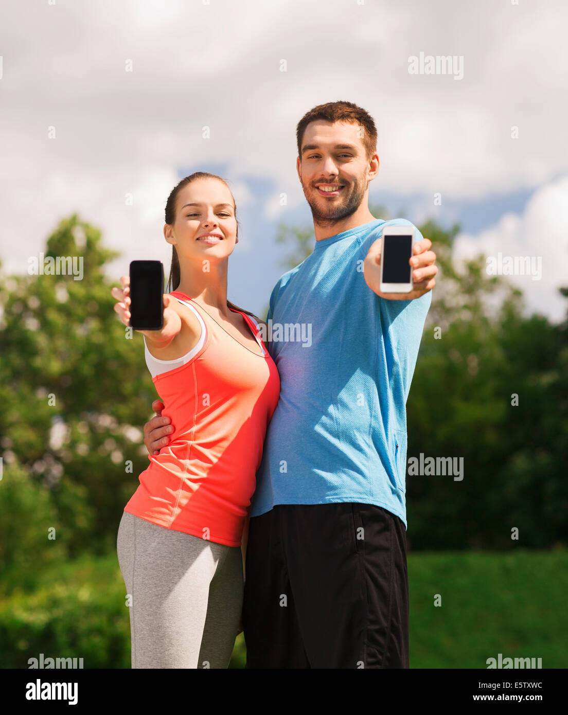 two smiling people with smartphones outdoors Stock Photo - Alamy