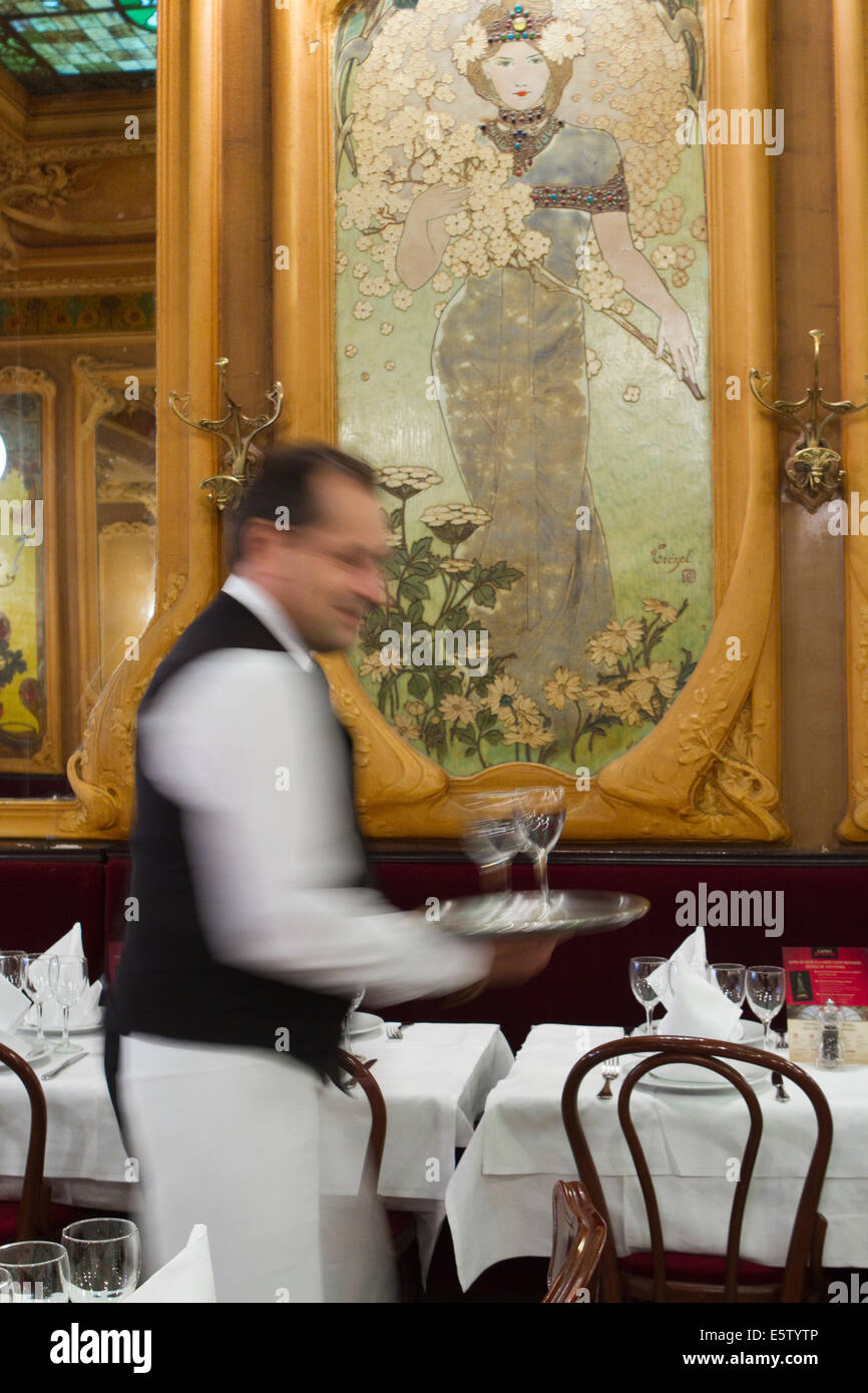 French waiter carrying a platter of wine glasses in Brasserie Julien ...