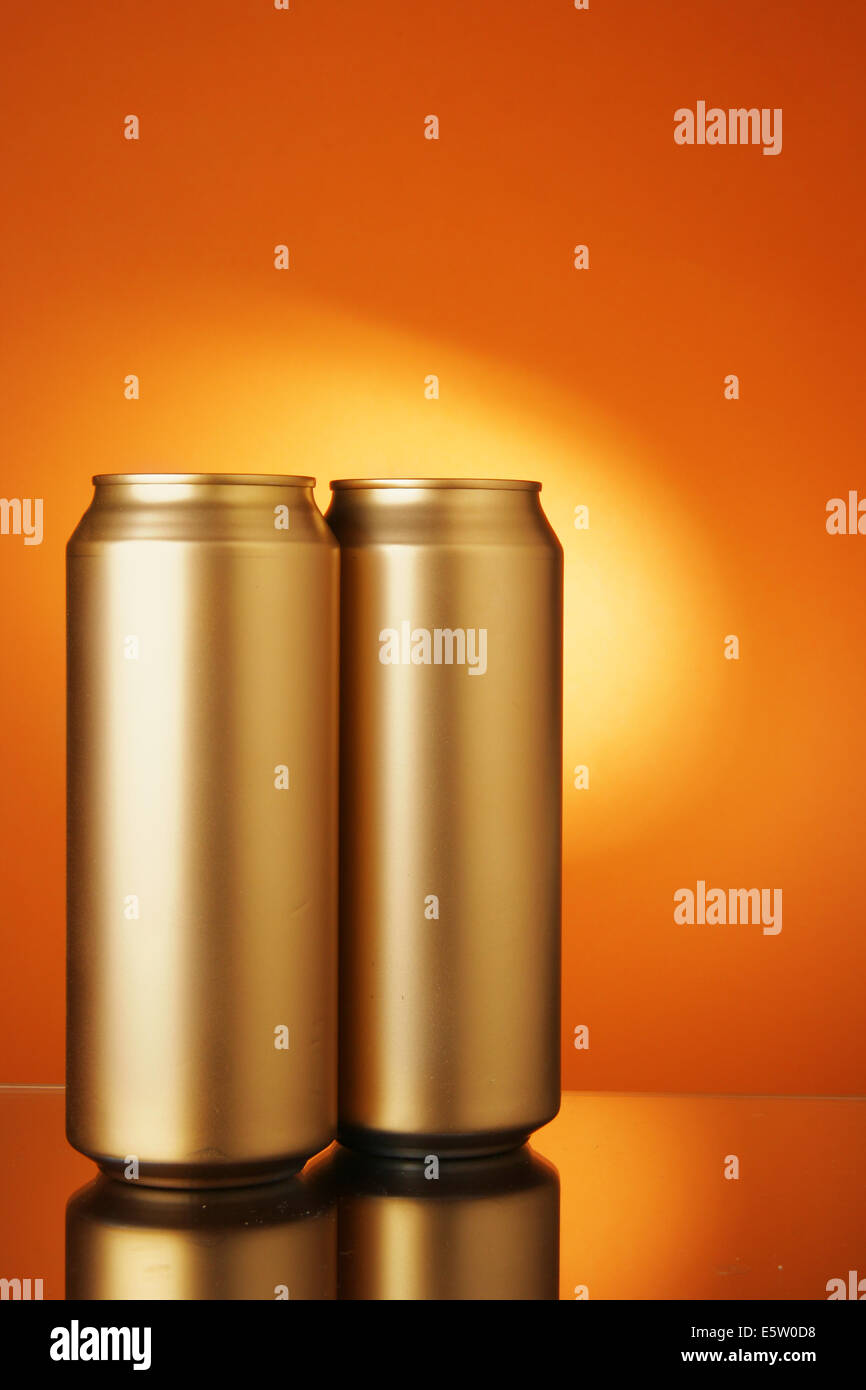 Two golden beer cans over orange background Stock Photo - Alamy