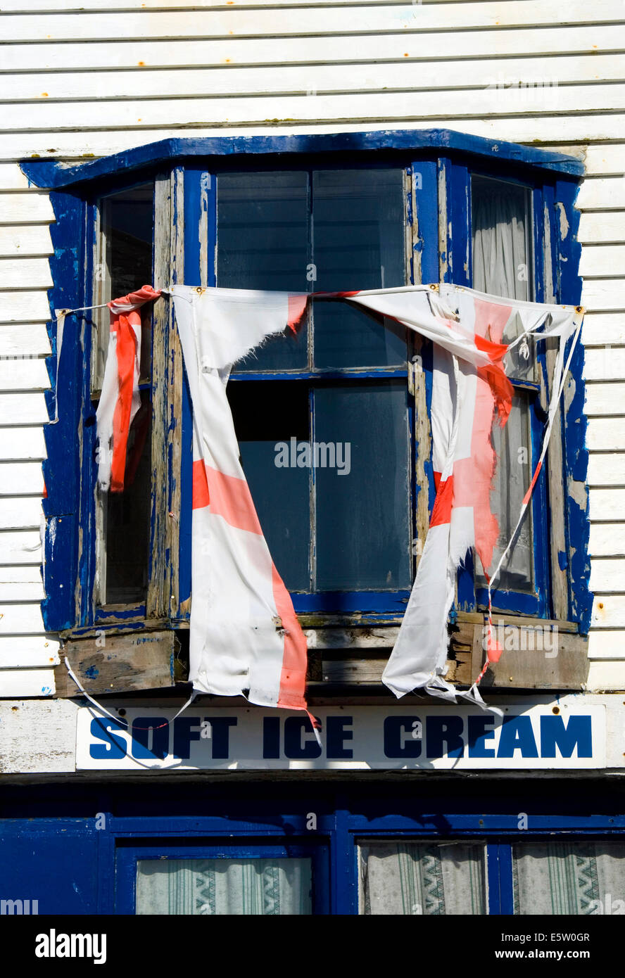 Tattered Union Jack flag hanging from window of ice cream parlour Stock ...