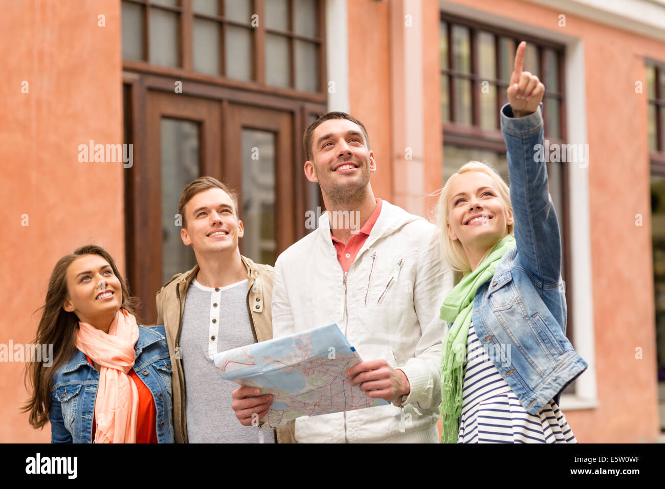 group of smiling friends with map exploring city Stock Photo - Alamy