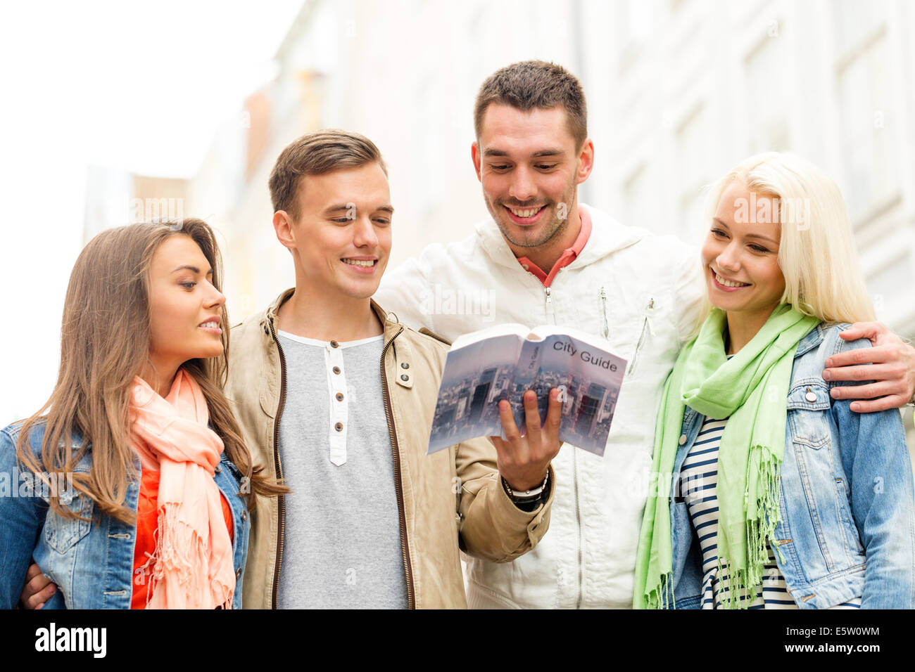 group of friends with city guide exploring town Stock Photo - Alamy