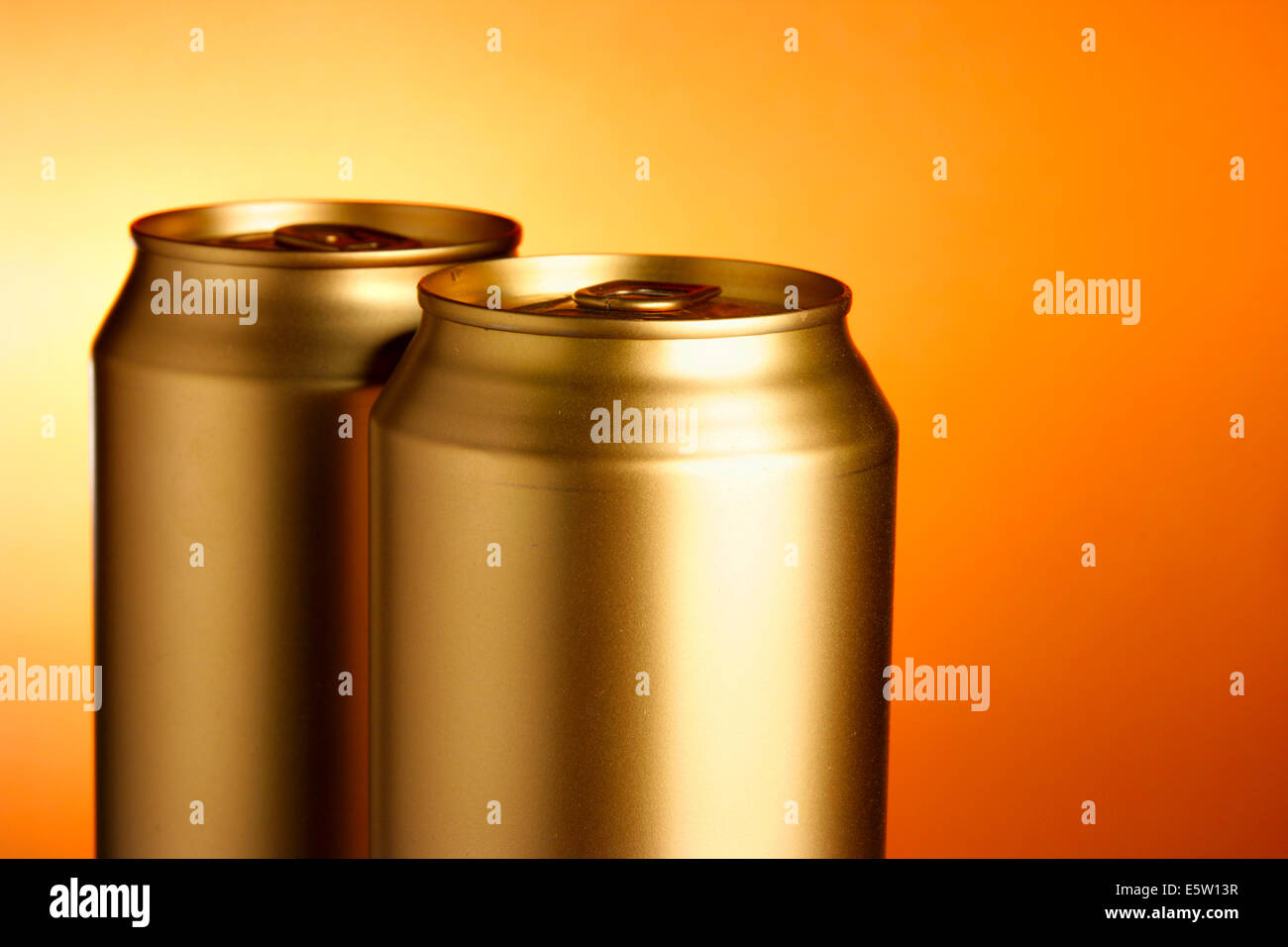 Golden beer cans close-up over orange background Stock Photo - Alamy