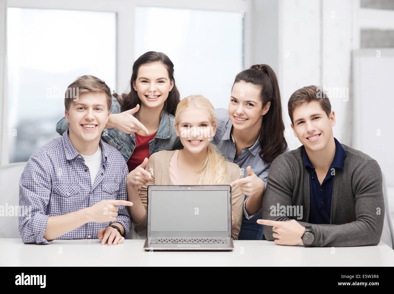 smiling students pointing to blank lapotop screen Stock Photo - Alamy