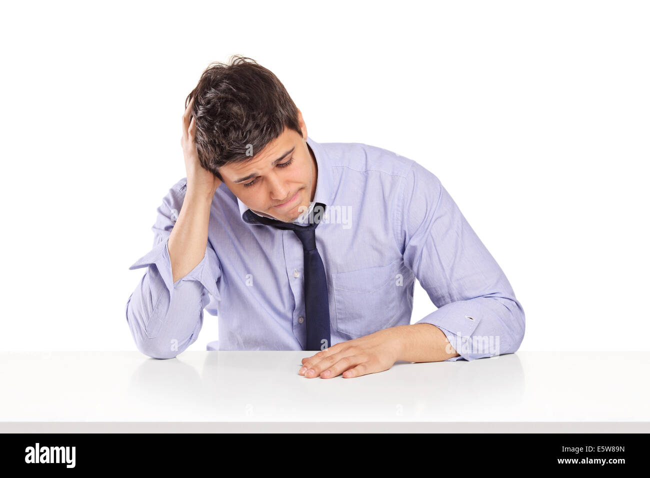Disappointed young man sitting on a table Stock Photo - Alamy