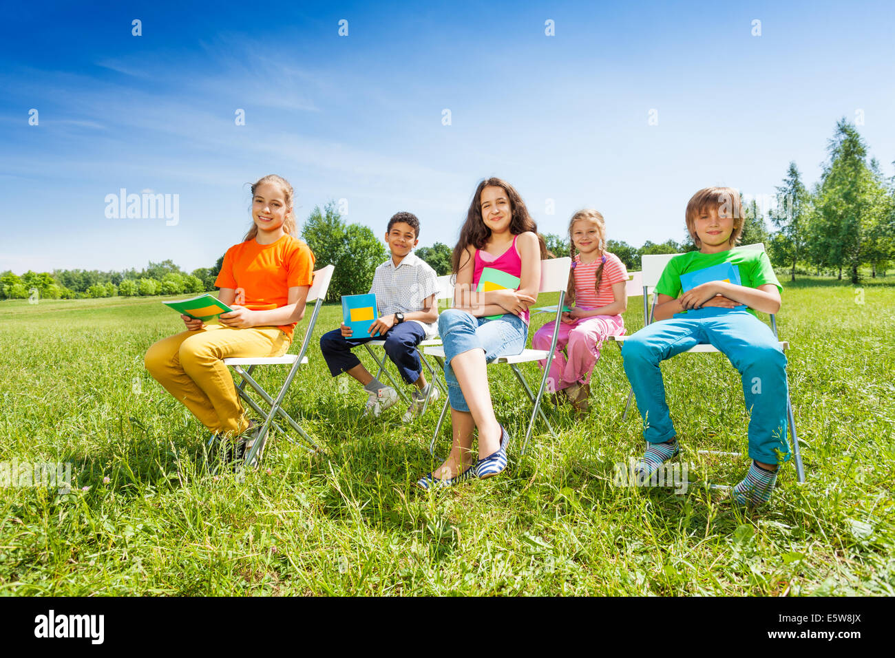 School children hold notebooks and sit on chairs Stock Photo - Alamy