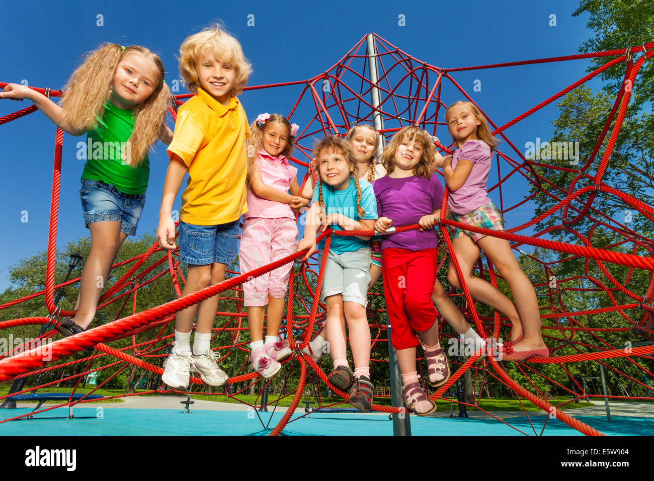Happy kids stand on red ropes of playground Stock Photo - Alamy