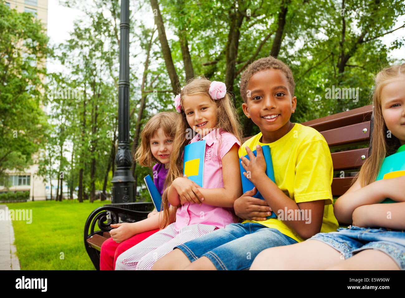 Looking kids sit together on bench and smile Stock Photo - Alamy