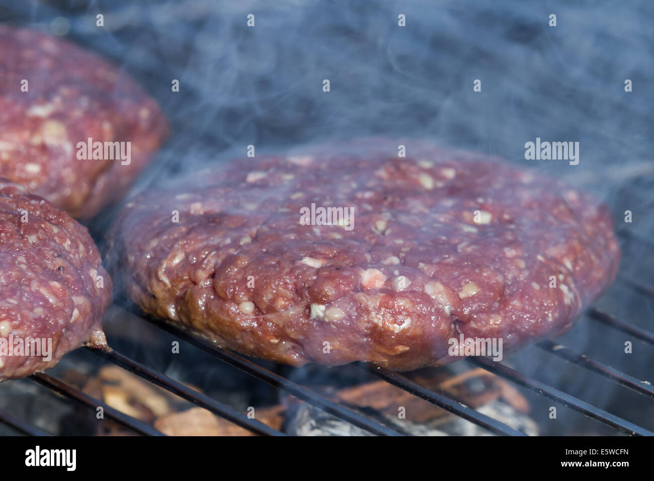 close up of hand formed hamburger patties on an outdoor grill with ...