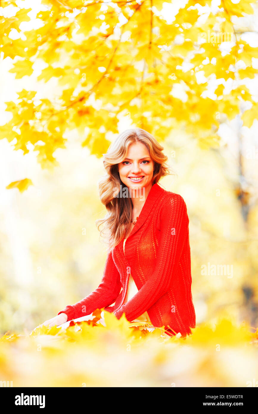Happy young woman sitting on autumn leaves in park Stock Photo - Alamy
