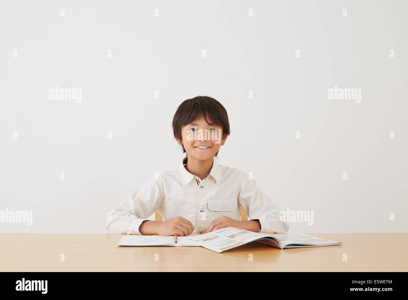 Young boy doing his homework on wooden desk Stock Photo - Alamy