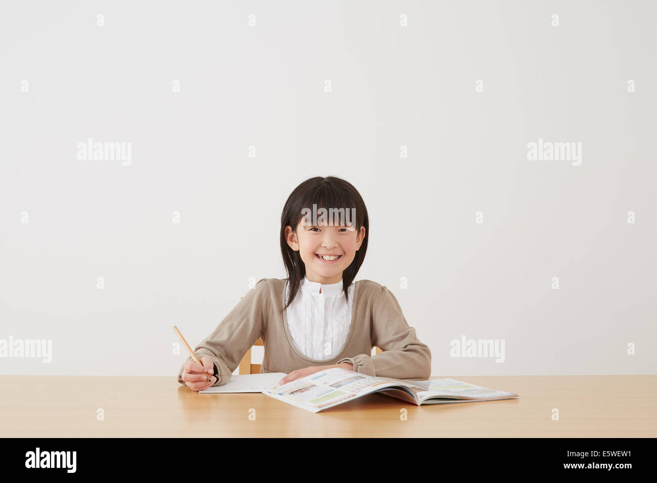 Young girl doing her homework on wooden desk Stock Photo - Alamy