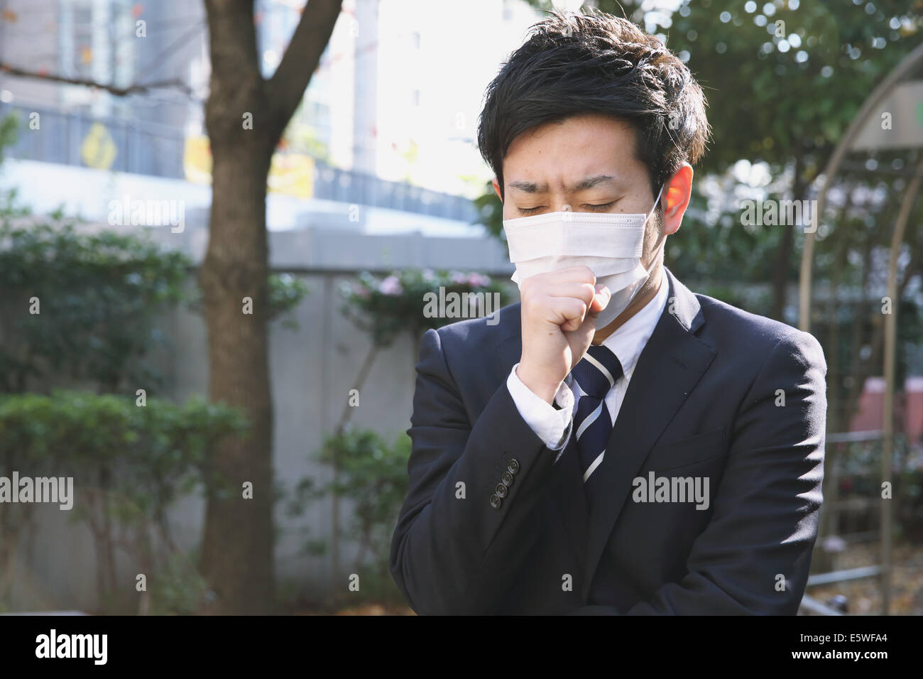 Sick Japanese young businessman in a suit at the park Stock Photo - Alamy