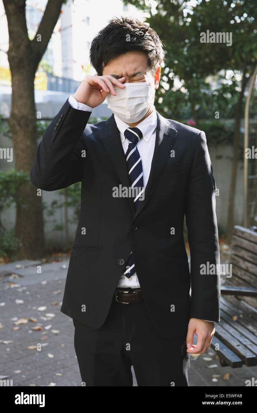 Sick Japanese young businessman in a suit at the park Stock Photo - Alamy