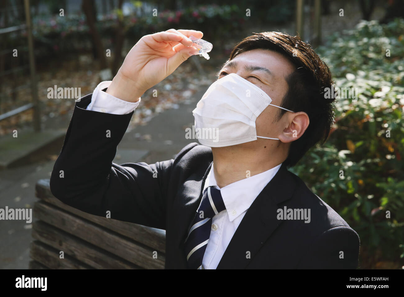 Sick Japanese young businessman in a suit at the park Stock Photo - Alamy
