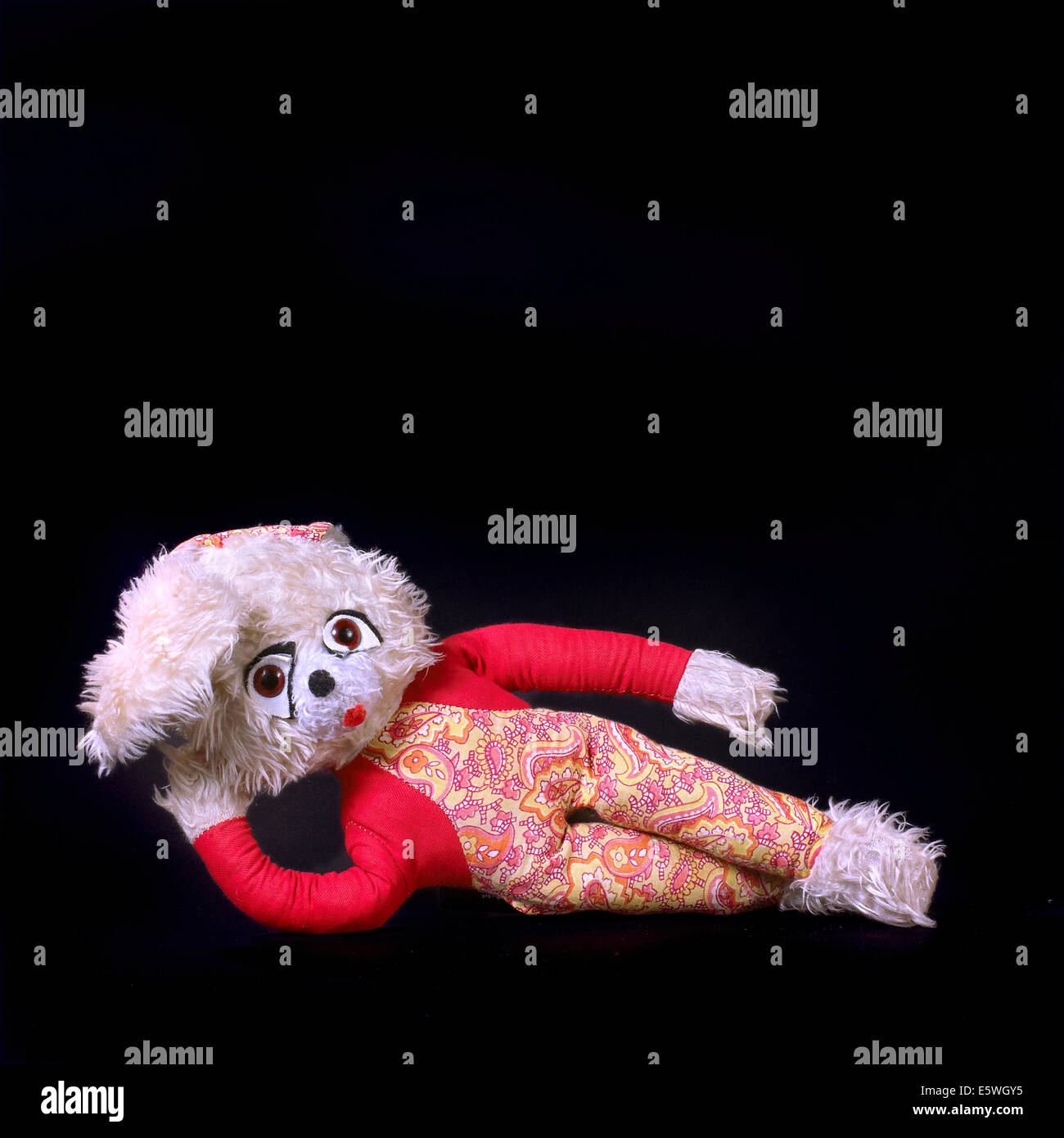 Studio shot of old worn soft toy. Vintage white rabbit with red jacket ...