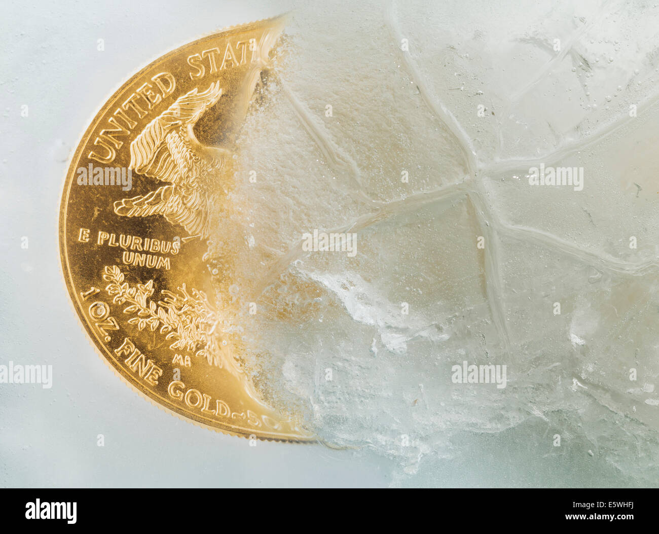 Gold eagle one ounce coin emerging from a frozen ice block - concept of ...