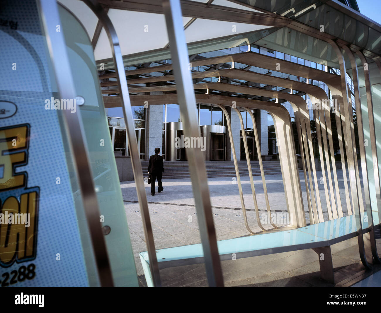 Modern bus stop with business man walking towards entrance of office at ...