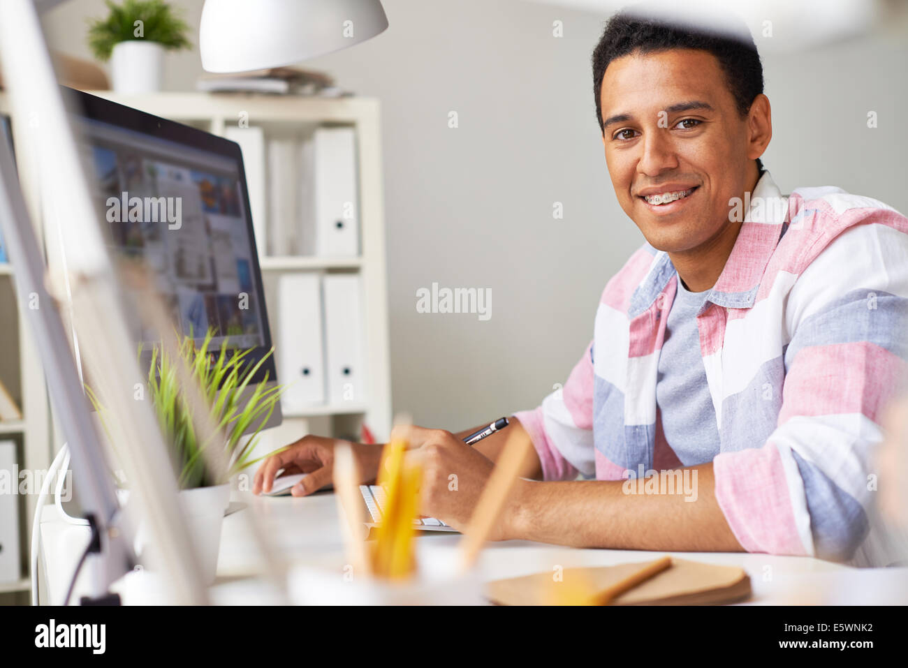 Smart guy looking at camera while sitting at workplace Stock Photo - Alamy