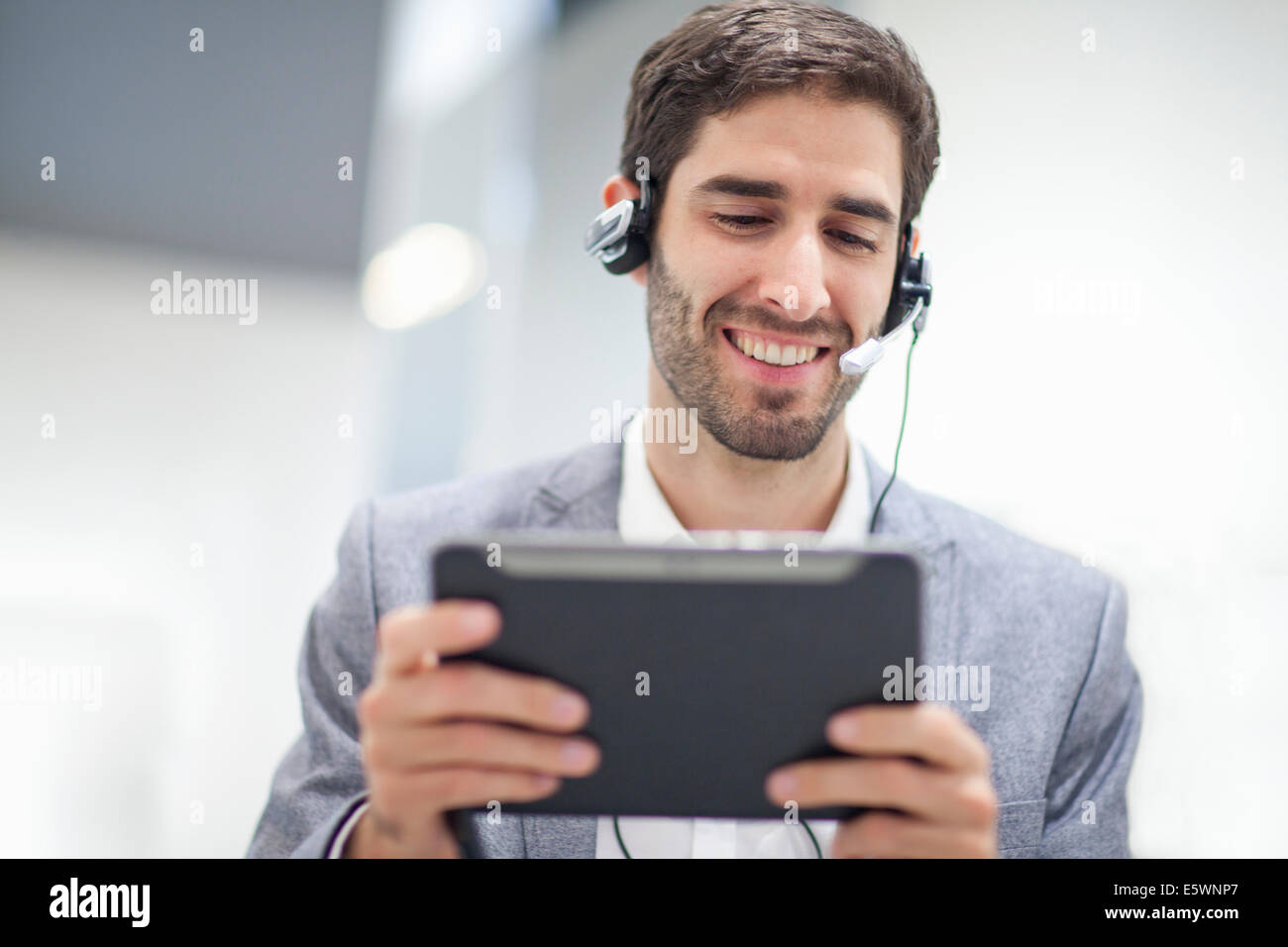 Young man wearing headset using digital tablet Stock Photo - Alamy