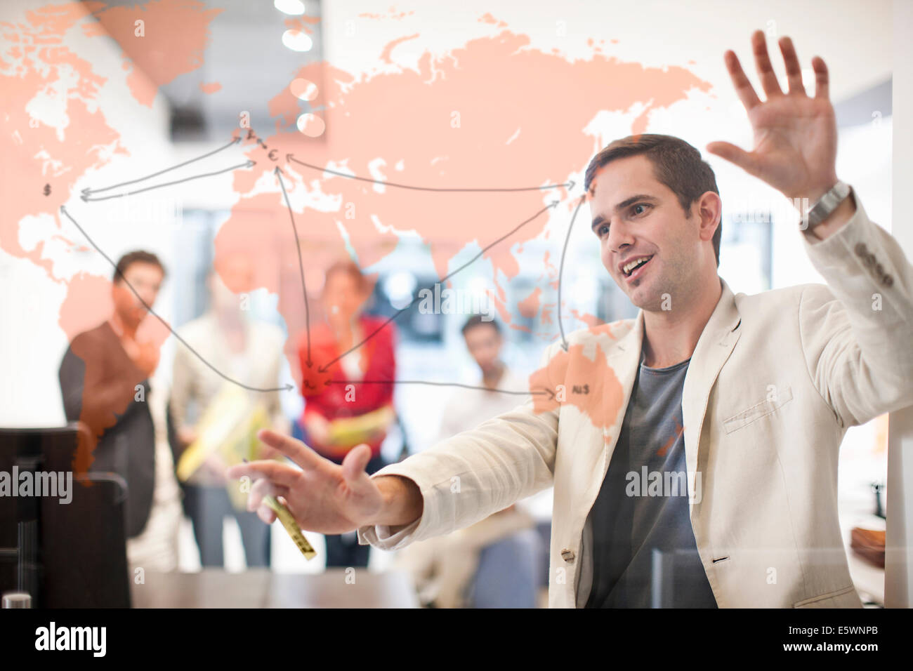 Man writing on glass screen, colleagues watching Stock Photo - Alamy