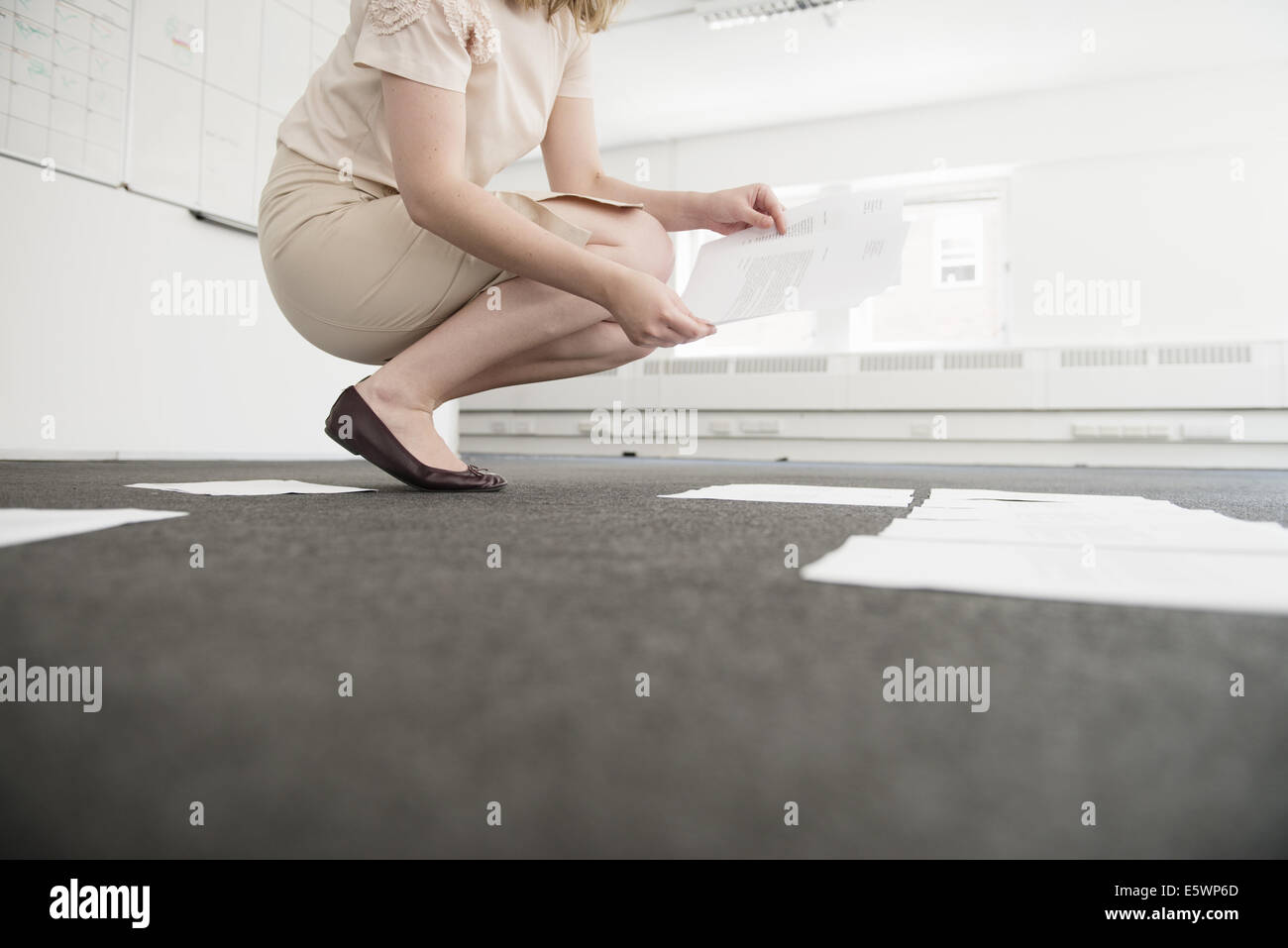 Young businesswoman organizing paperwork on empty office floor Stock ...