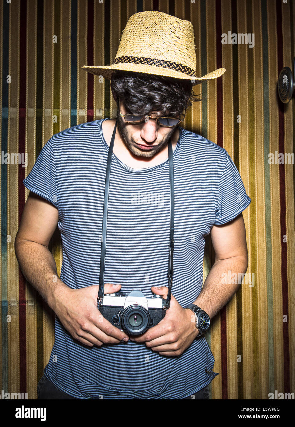Portrait of young man looking down at vintage camera Stock Photo - Alamy