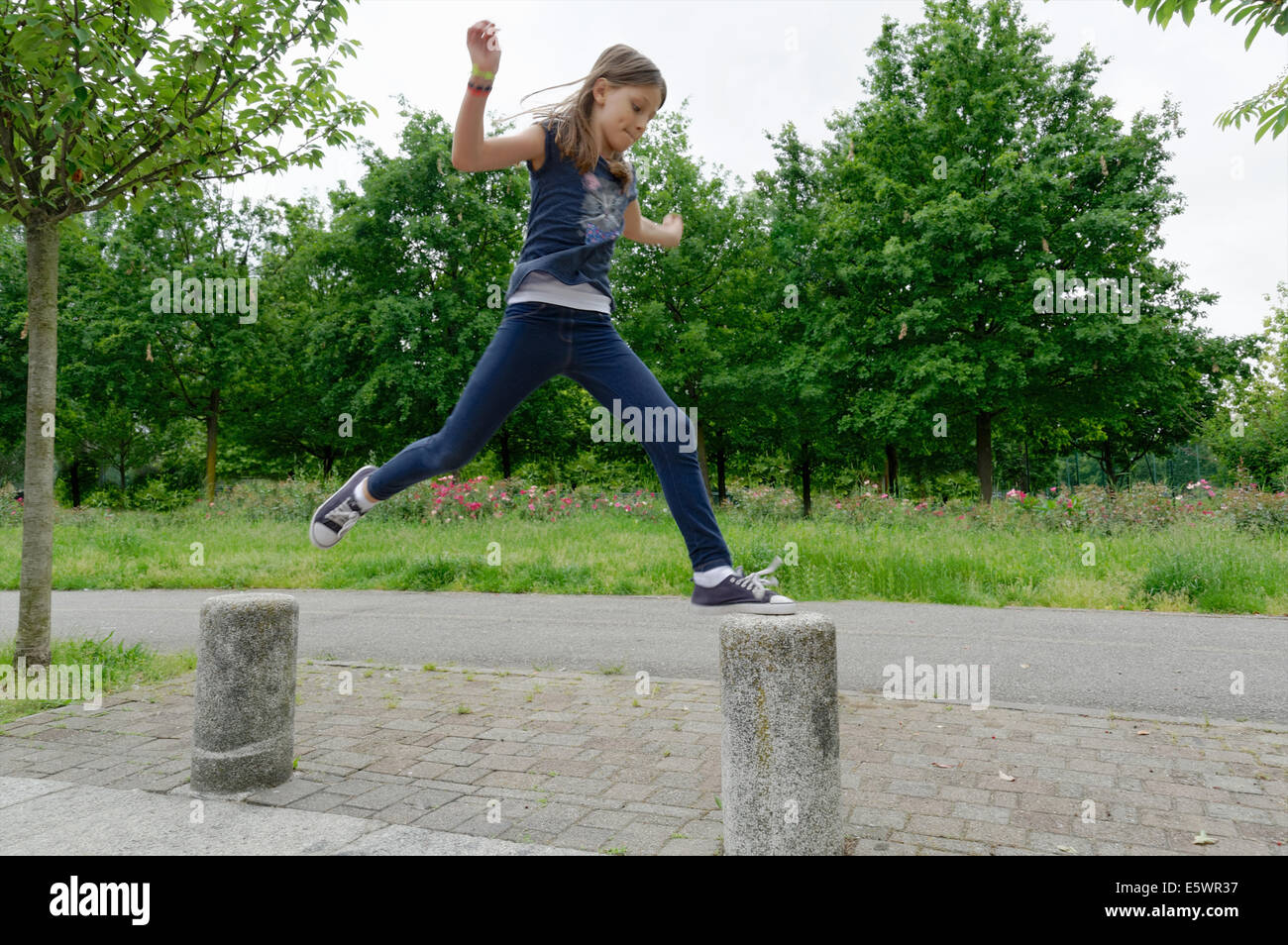Girl jumping bollards mid air in park Stock Photo - Alamy
