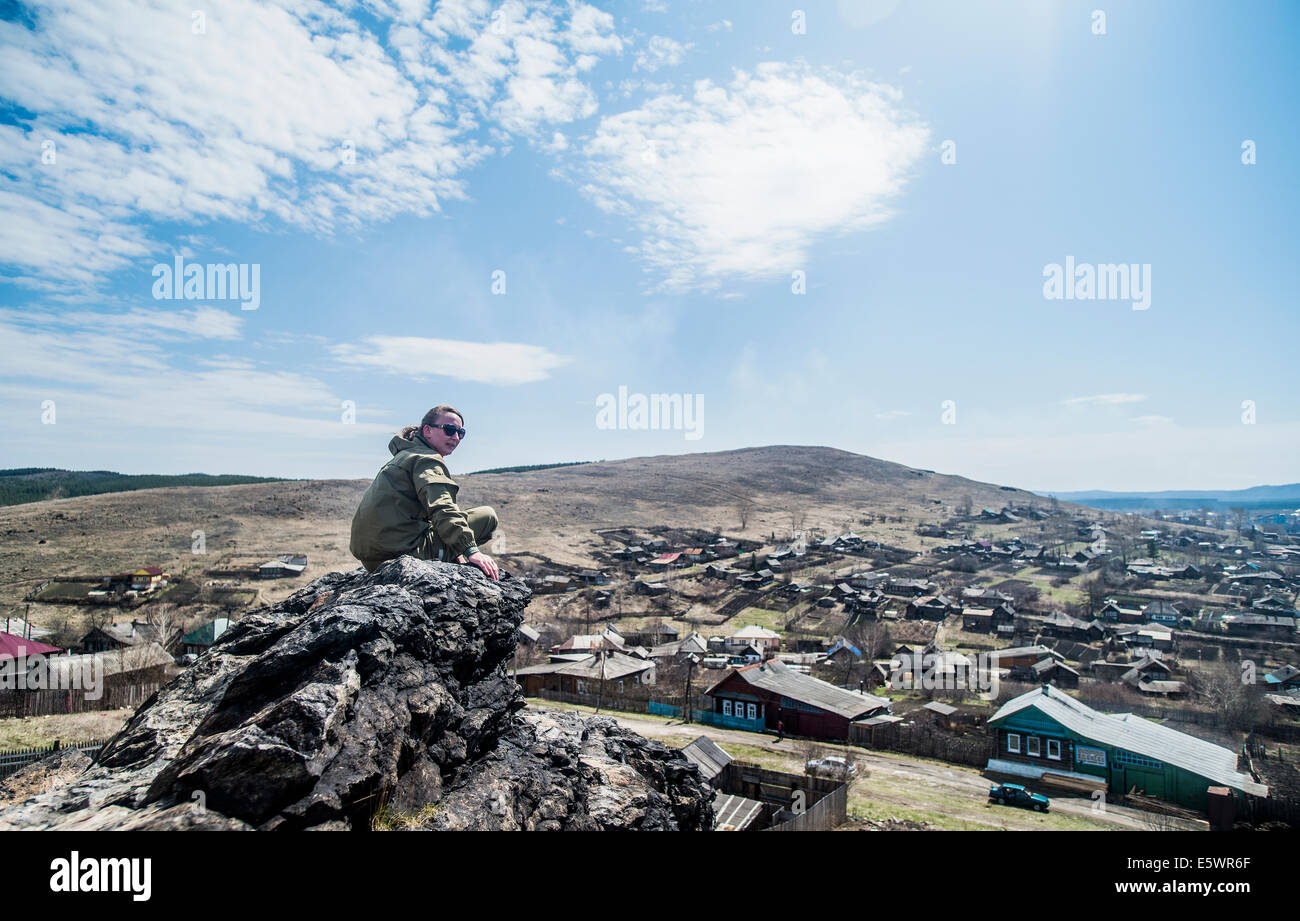 Young female hiker looking over shoulder on top of mountain rock Stock ...