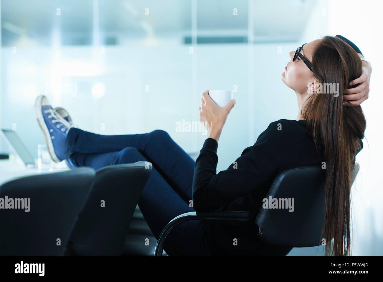 Female office worker leaning back with feet up on conference table ...