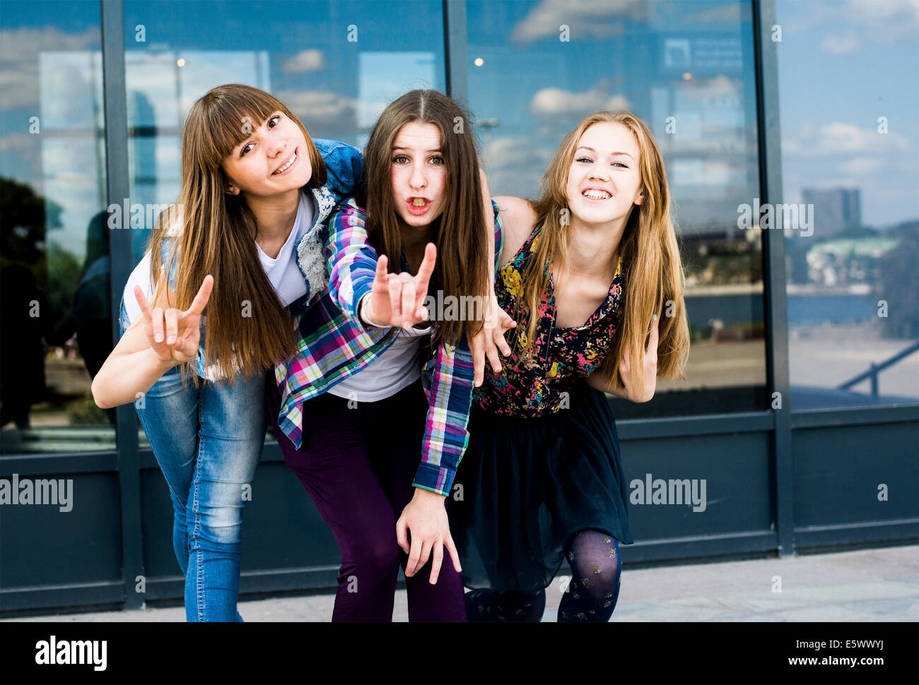Three young women leaning forward in a row and making I love you hand ...