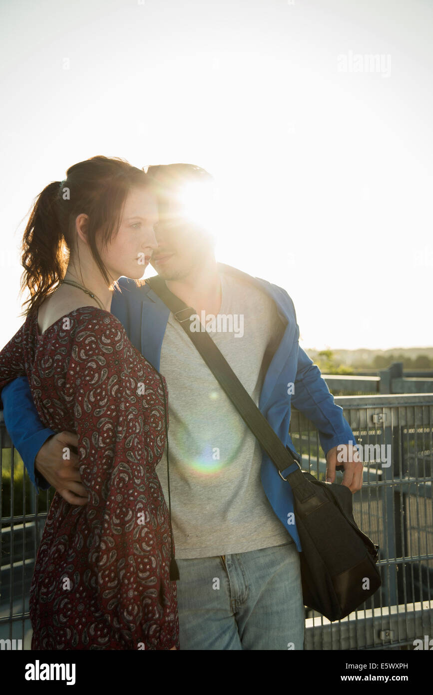 Romantic young couple leaning against fence on rooftop Stock Photo - Alamy