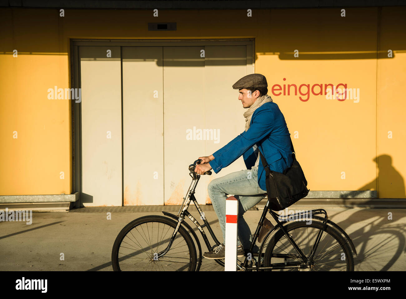 Young man cycling along urban street Stock Photo - Alamy