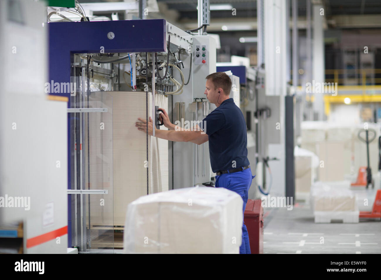 Worker using machine in paper packaging factory Stock Photo - Alamy
