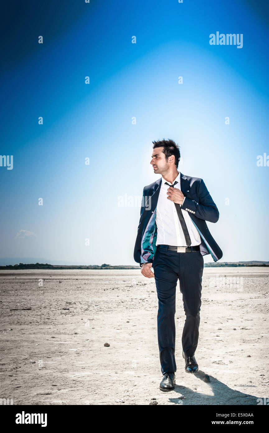 Young businessman striding through desert landscape alone Stock Photo ...