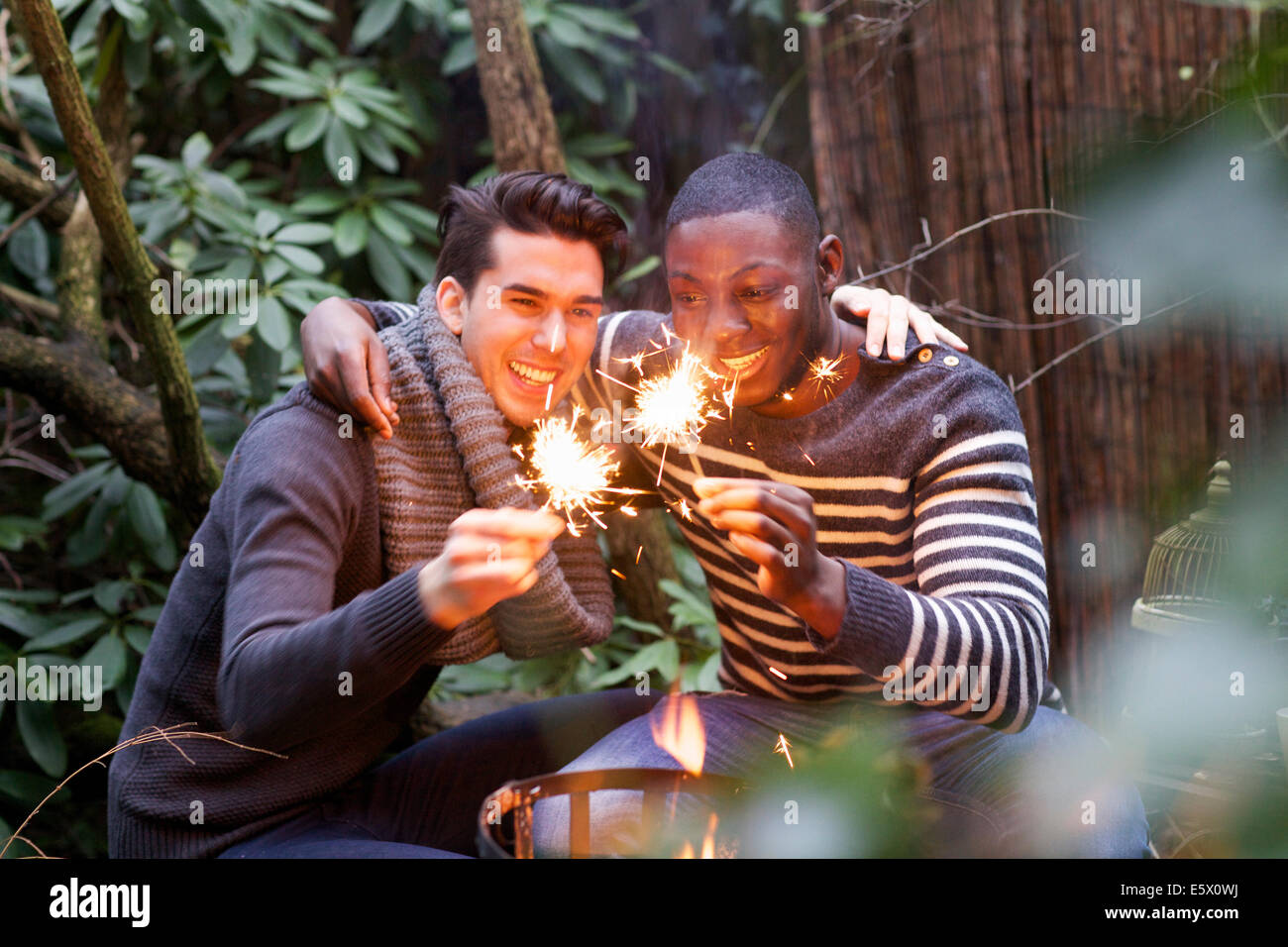 Two young men crouching in front of garden fire with sparklers Stock ...