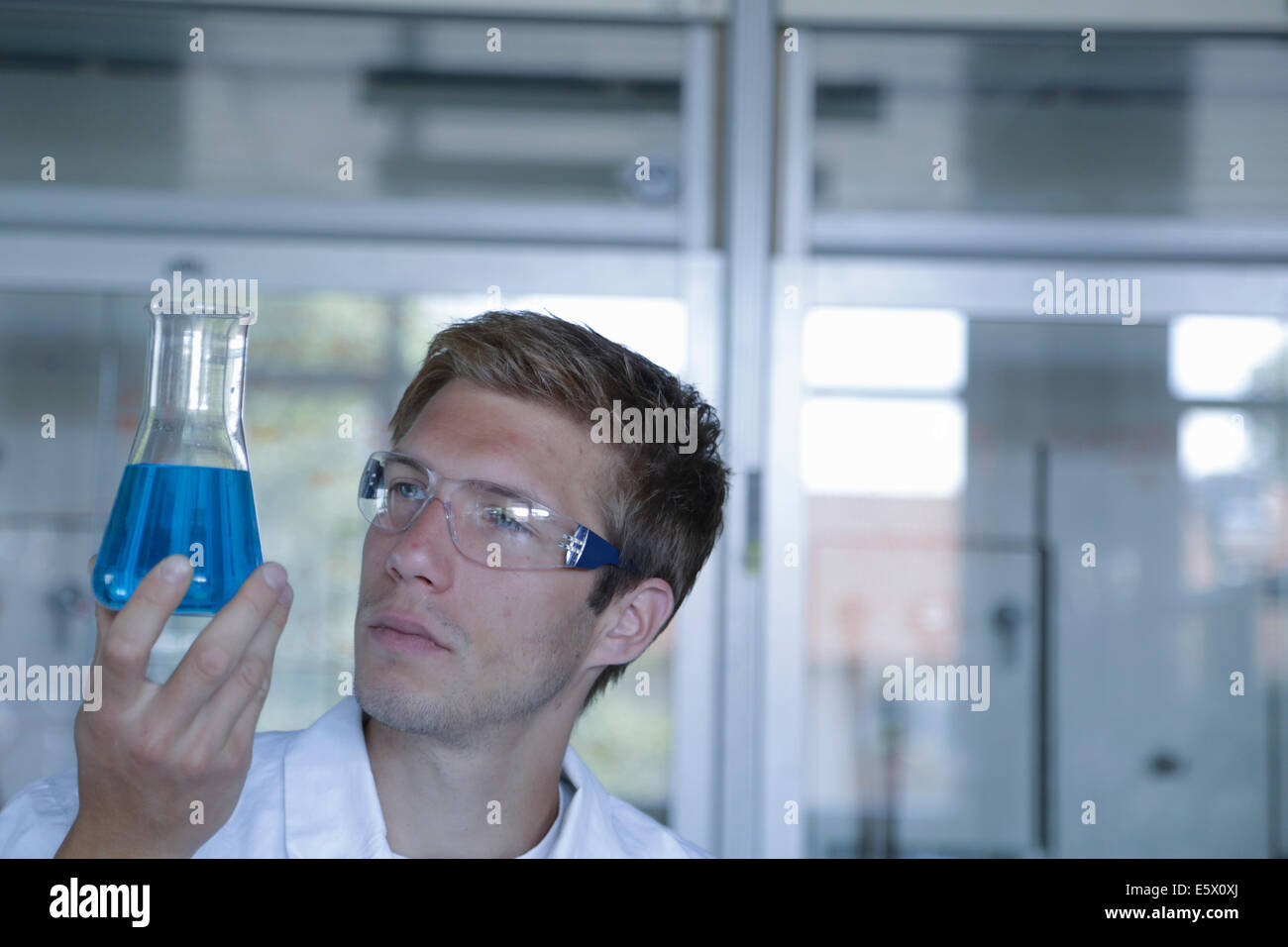 Young male scientist holding up erlenmeyer flask in lab Stock Photo - Alamy