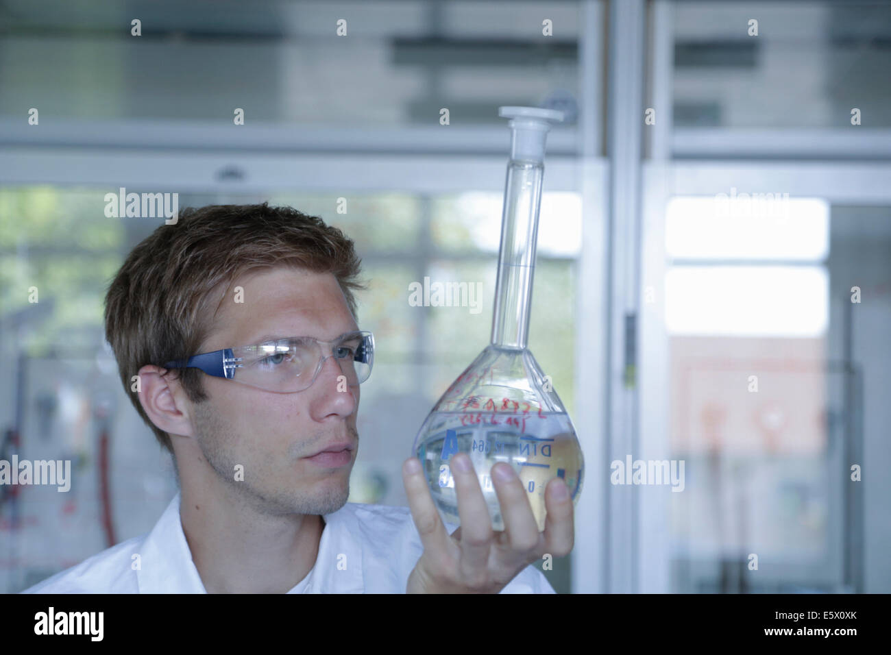 Young male scientist holding up volumetric flask in lab Stock Photo - Alamy