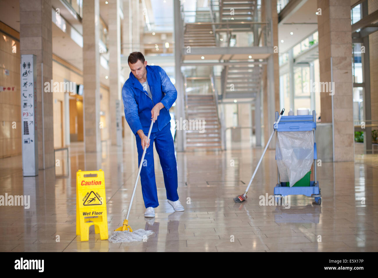 Male cleaner mopping in office atrium Stock Photo - Alamy