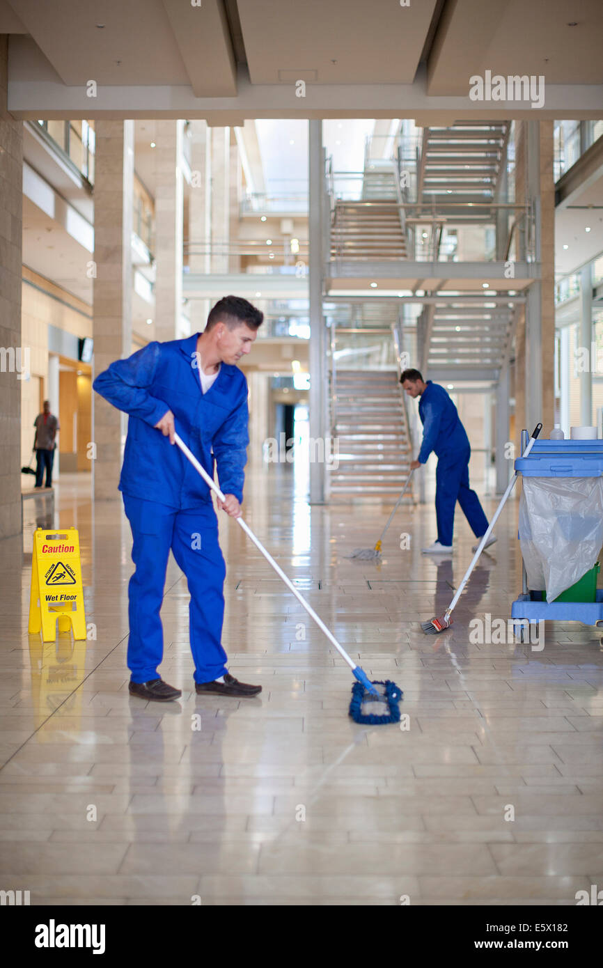 Male cleaners mopping in office atrium Stock Photo - Alamy