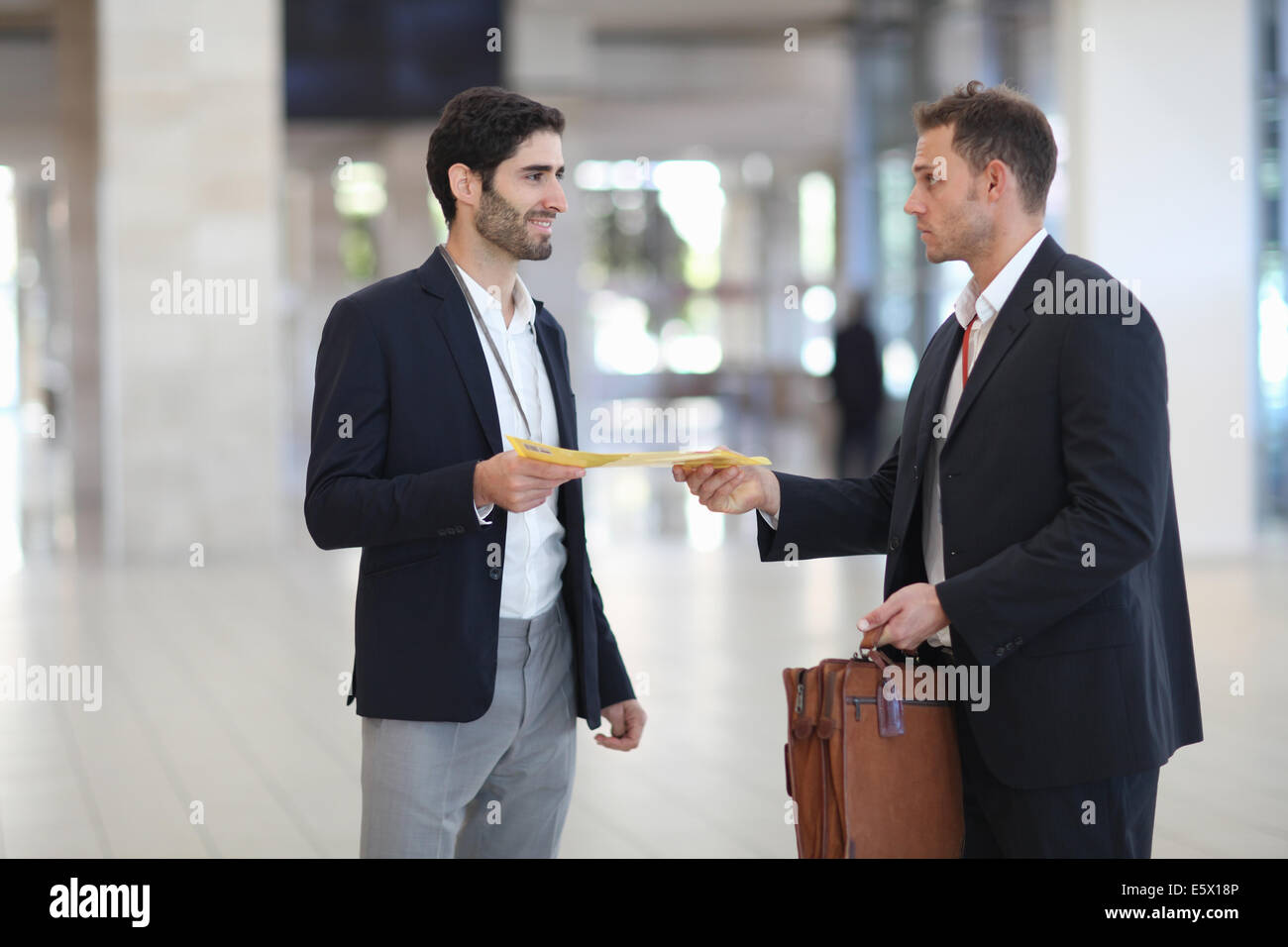 Office worker handing paperwork to businessman in conference centre ...